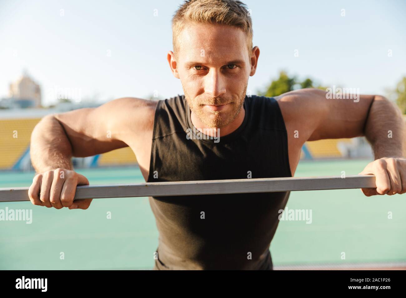 Image of handsome sportsman doing workout by metal railing at stadium ...