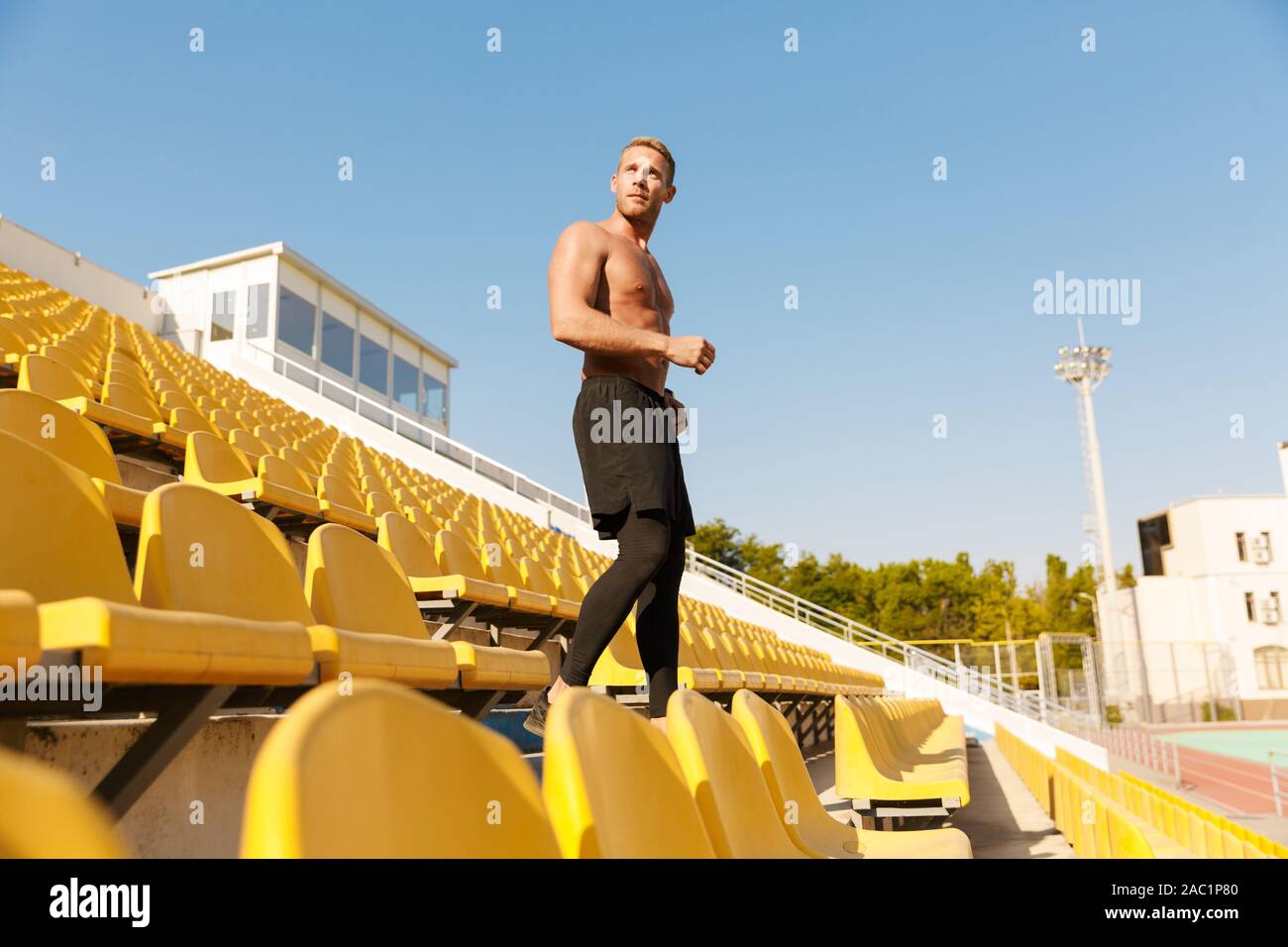 Image of a strong handsome young sports man outdoors at stadium walking ...