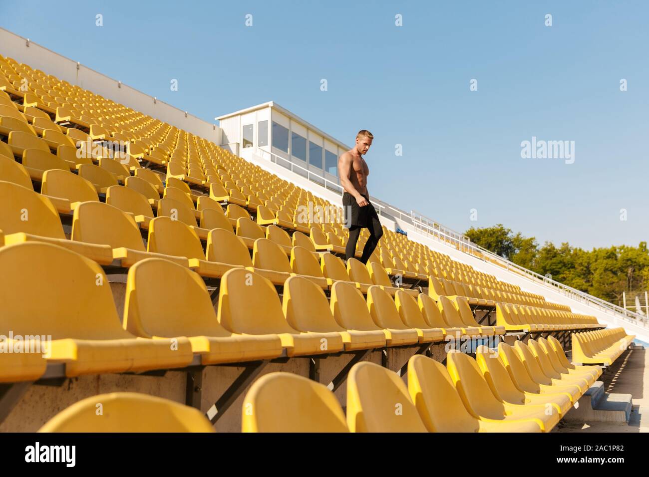 Image of a strong handsome young sports man outdoors at stadium walking ...