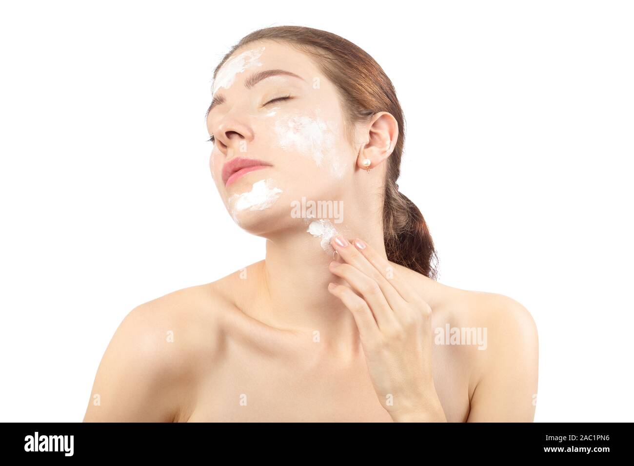 serious young woman applying cream on her face skin, isolated on white ...