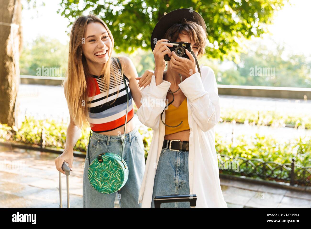 Photo of two cheerful attractive women taking photo on retro camera ...