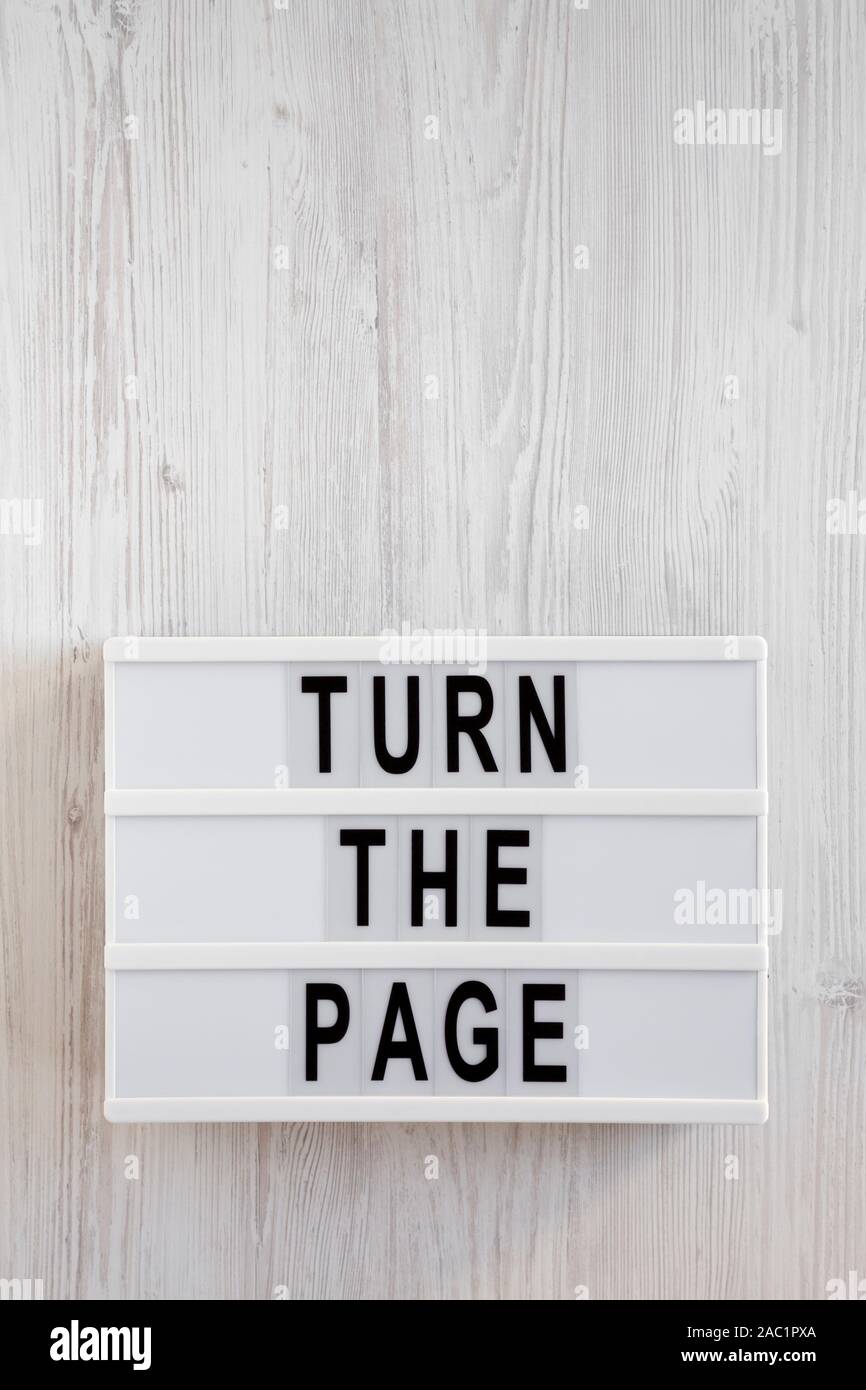 'Turn the page' words on a modern board on a white wooden surface, top ...