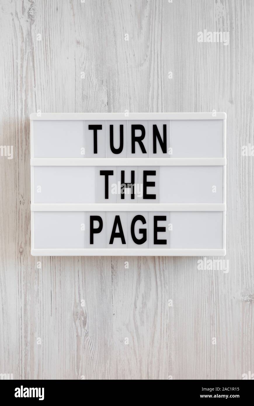 'Turn the page' words on a lightbox on a white wooden background, top ...