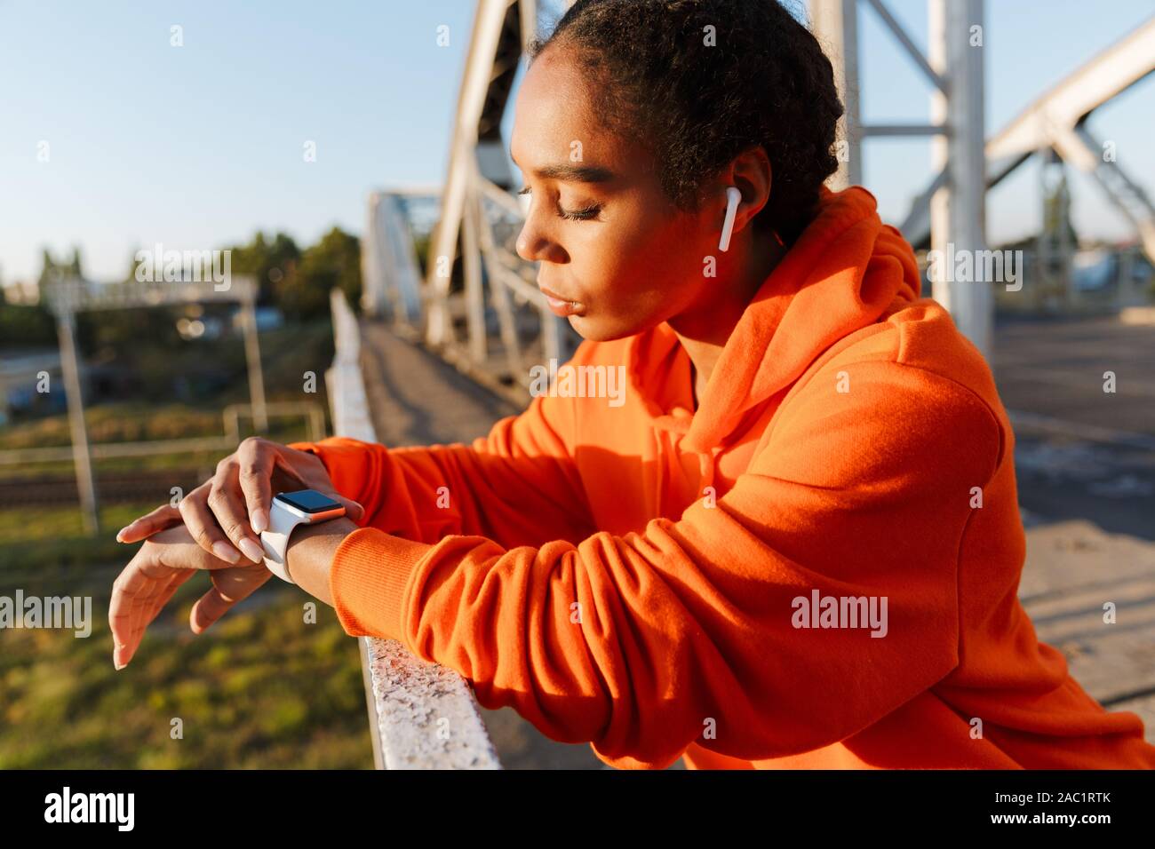 Photo of african american thinking woman in sportswear using earpods ...