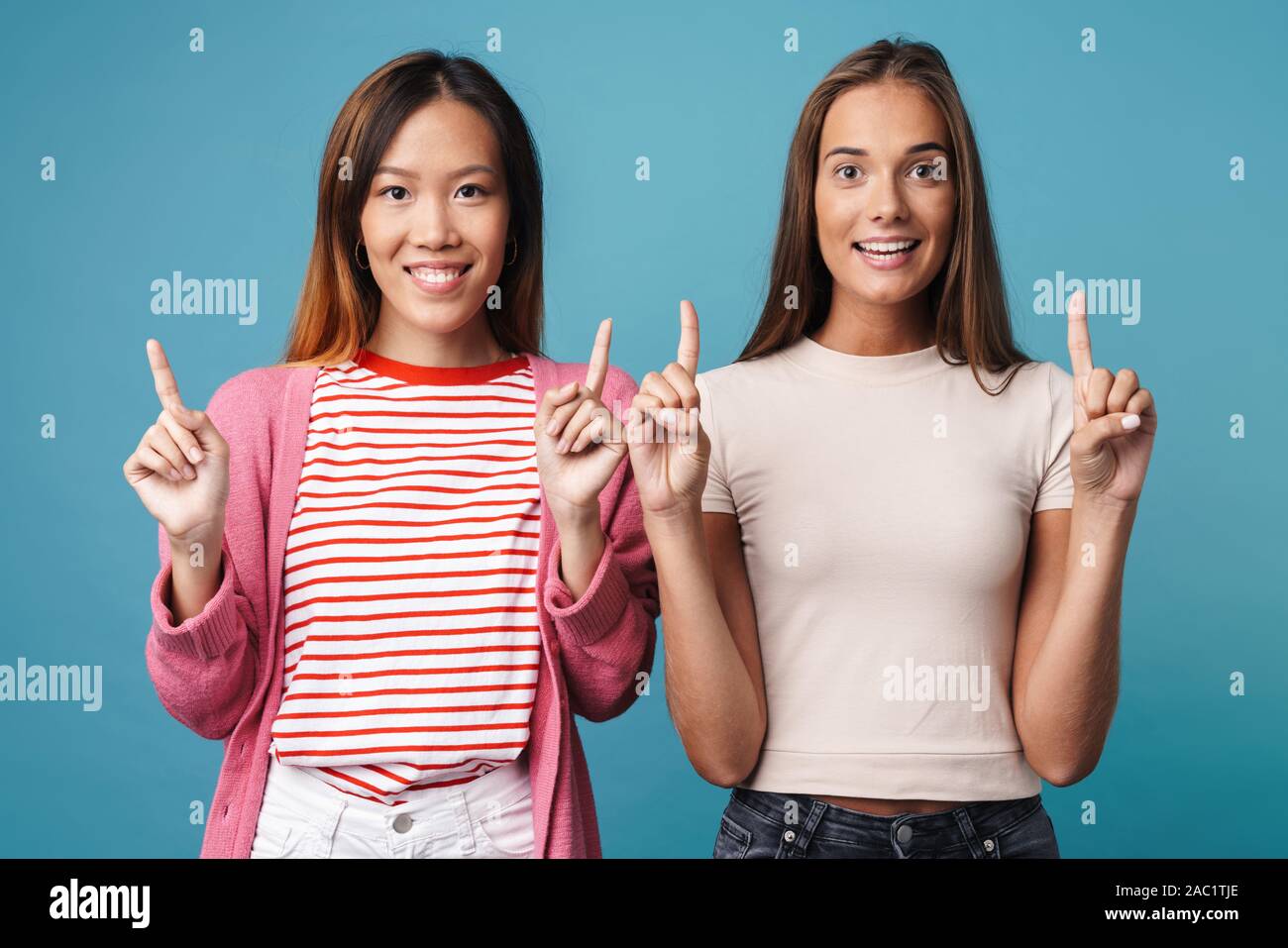 Portrait of multinational delighted women smiling and pointing fingers ...