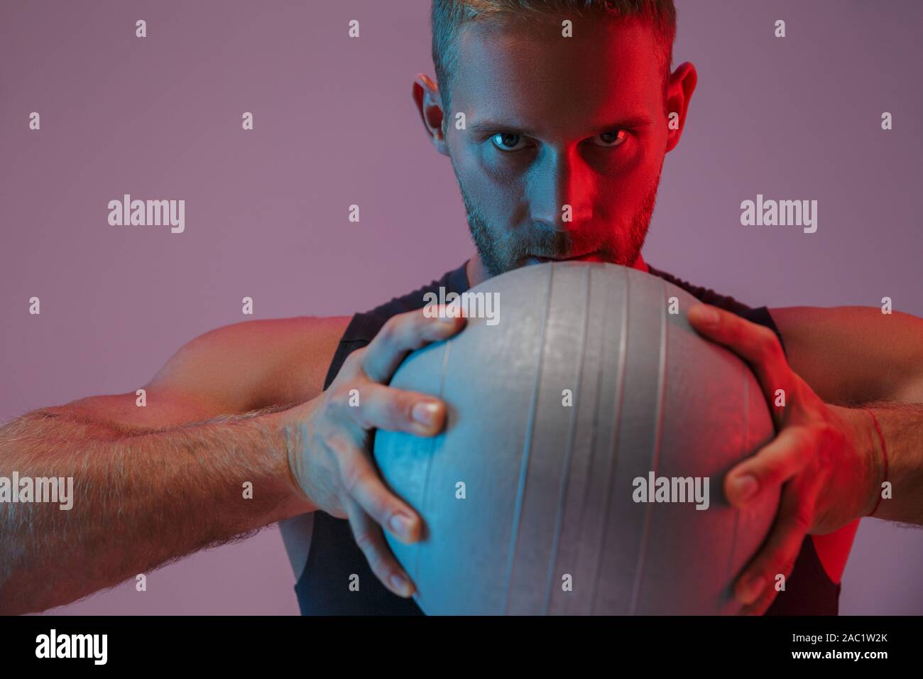 Image of a serious young sports man posing isolated over neon lights ...