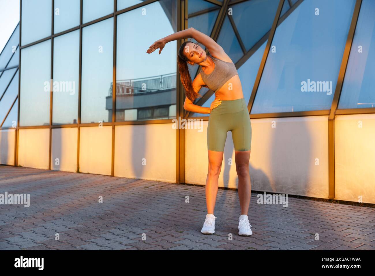 Young woman doing stretching exercise glass facade hi-res stock photography and images - Alamy