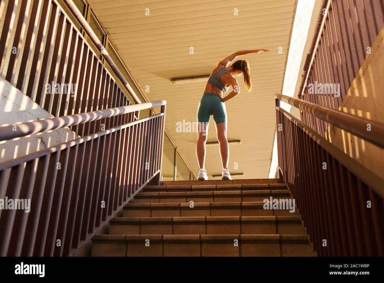 Attractive young fitness girl doing exercises on a balcony outdoors ...