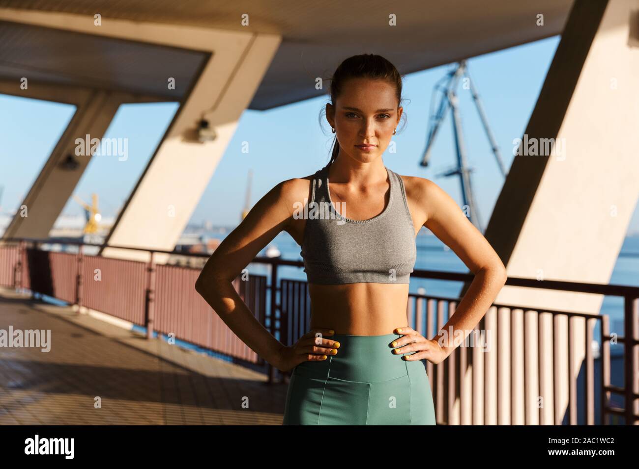 Exhausted fit young sportsgirl resting after jogging while standing on ...