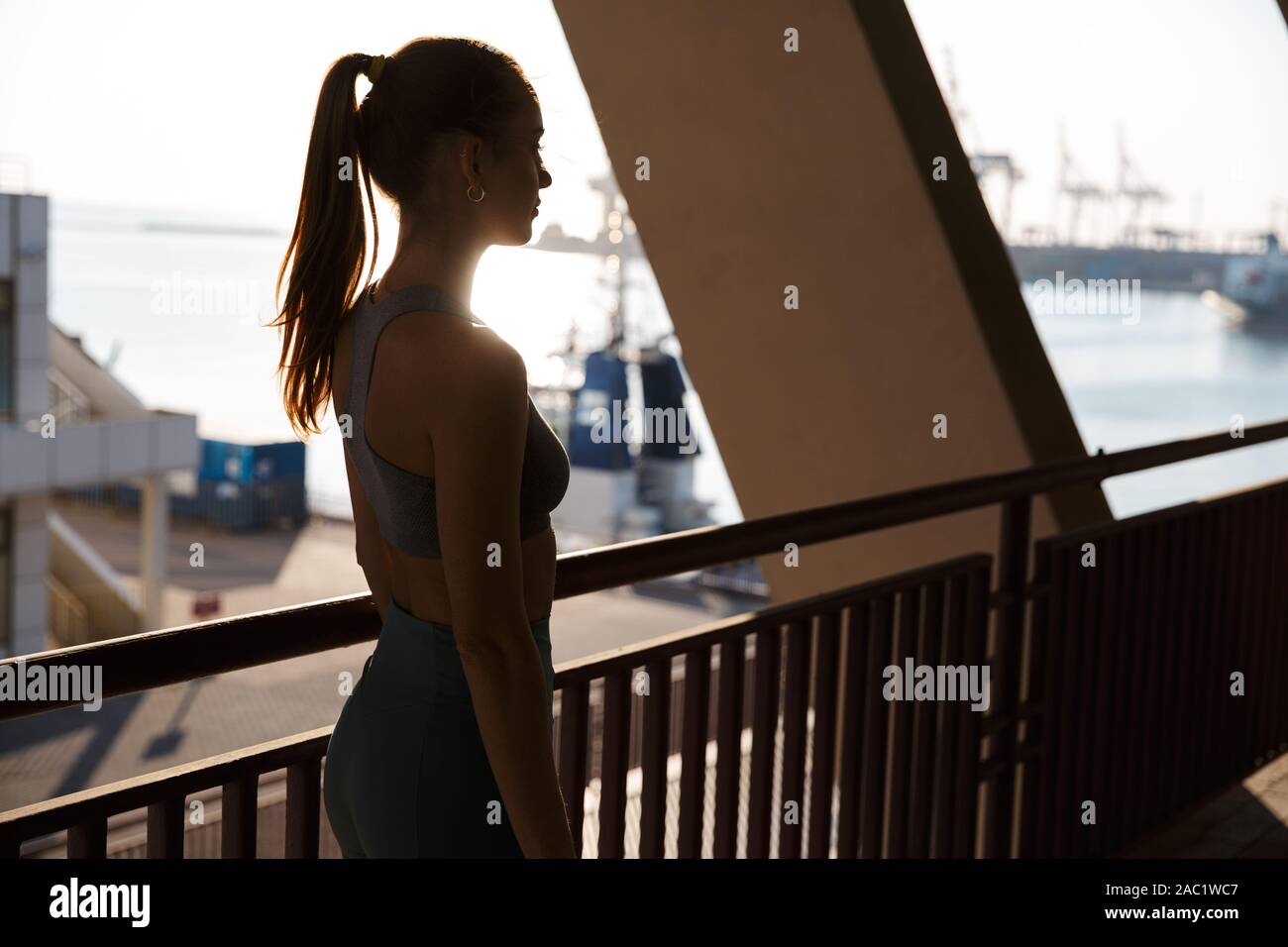 Beautiful fit young sportsgirl resting after jogging while standing on ...