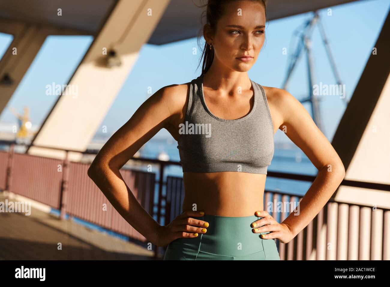 Exhausted fit young sportsgirl resting after jogging while standing on ...