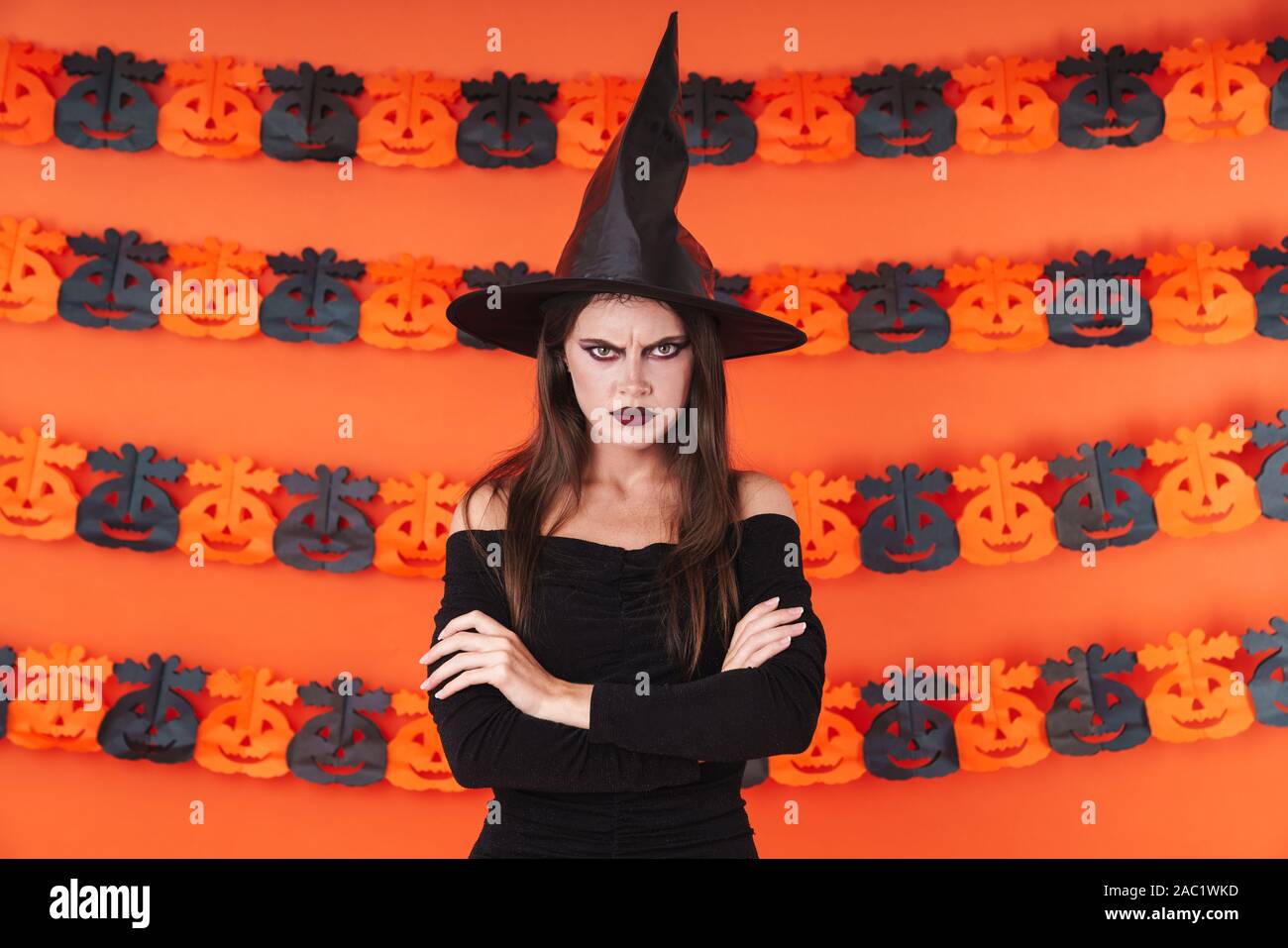 Image of angry witch girl in black halloween costume standing with arms ...