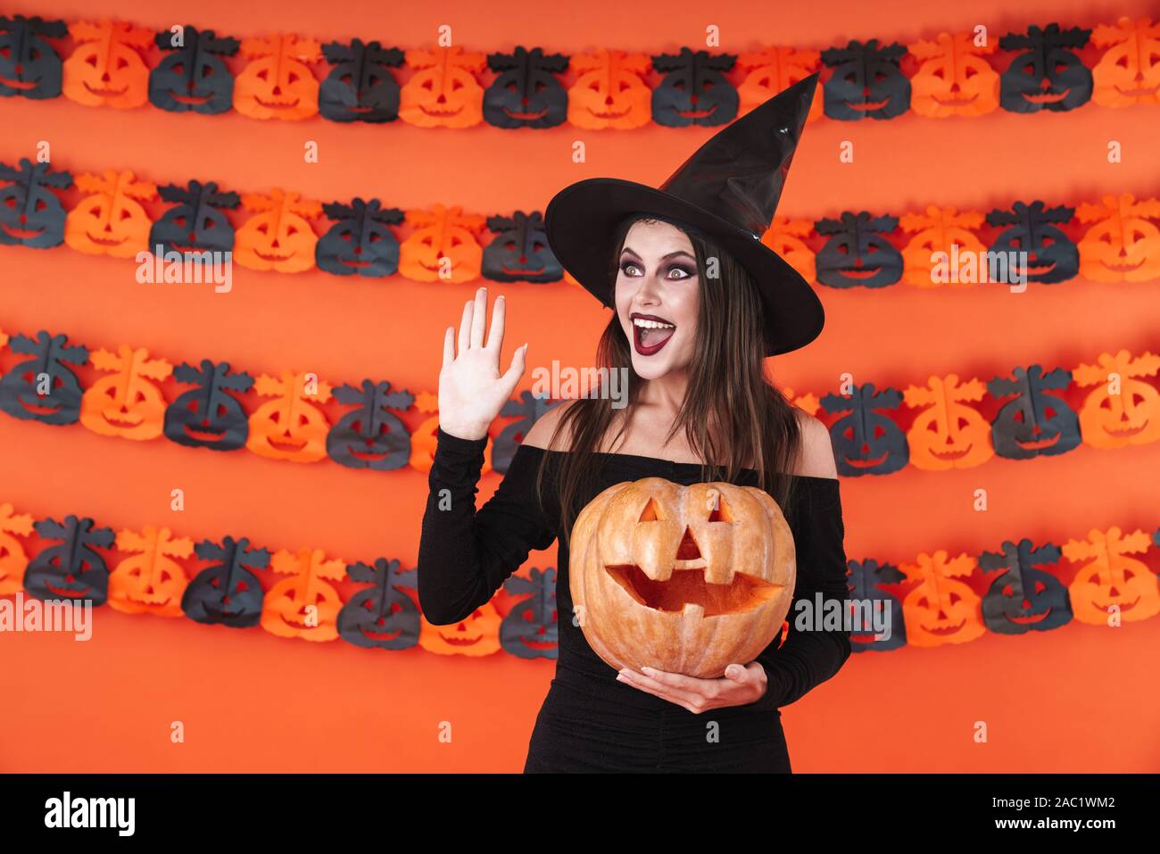 Image of excited witch girl in black halloween costume holding carved ...