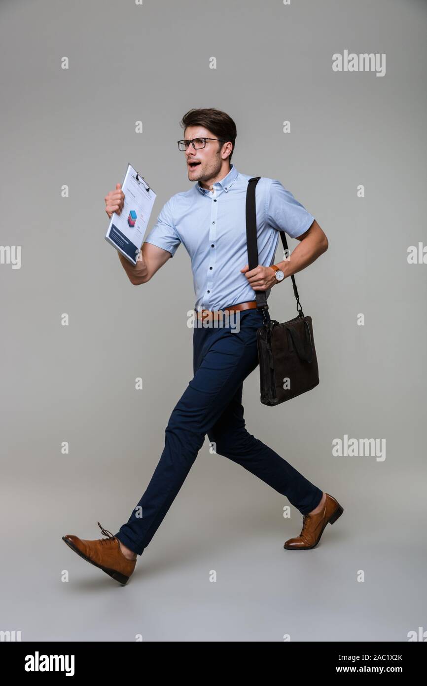Picture of a nervous business man walking running isolated over grey ...