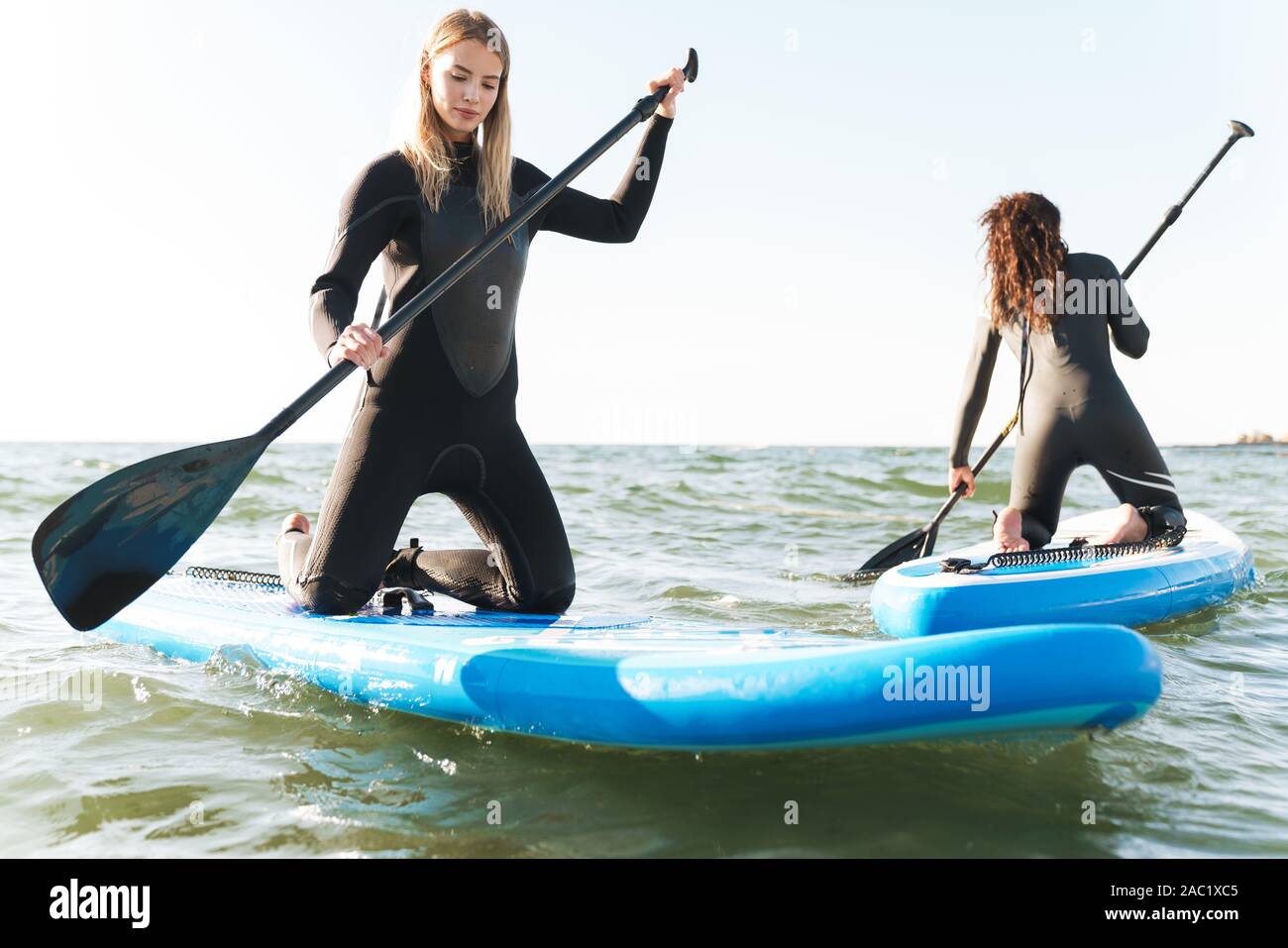 Image of a young beautiful two women on a kayaks outdoors at the beach ...
