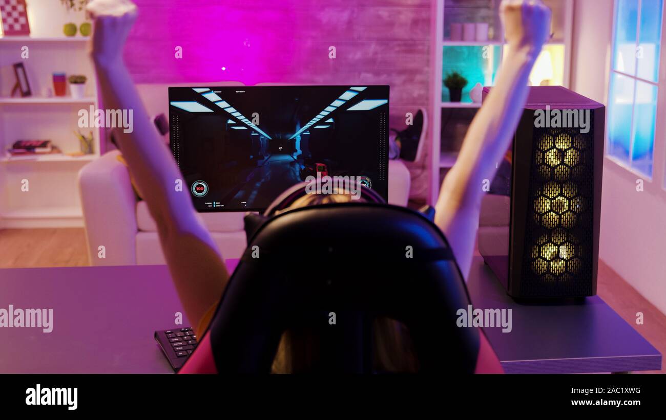 Happy blonde girl winning at a shooter game. She is playing on a ...