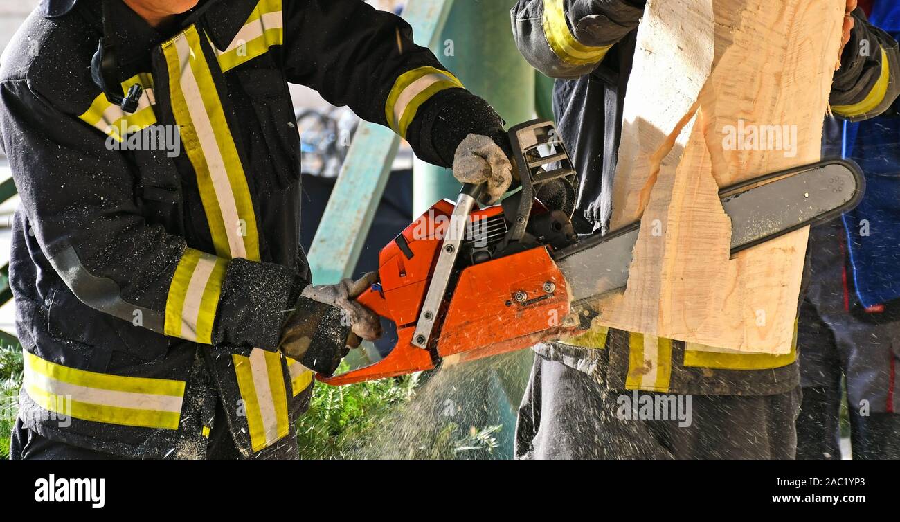 Firefighter works with a chainsaw outdoor Stock Photo - Alamy