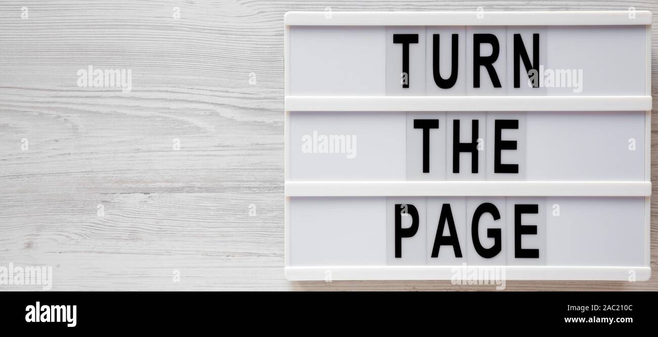 'Turn the page' words on a modern board on a white wooden surface, top ...