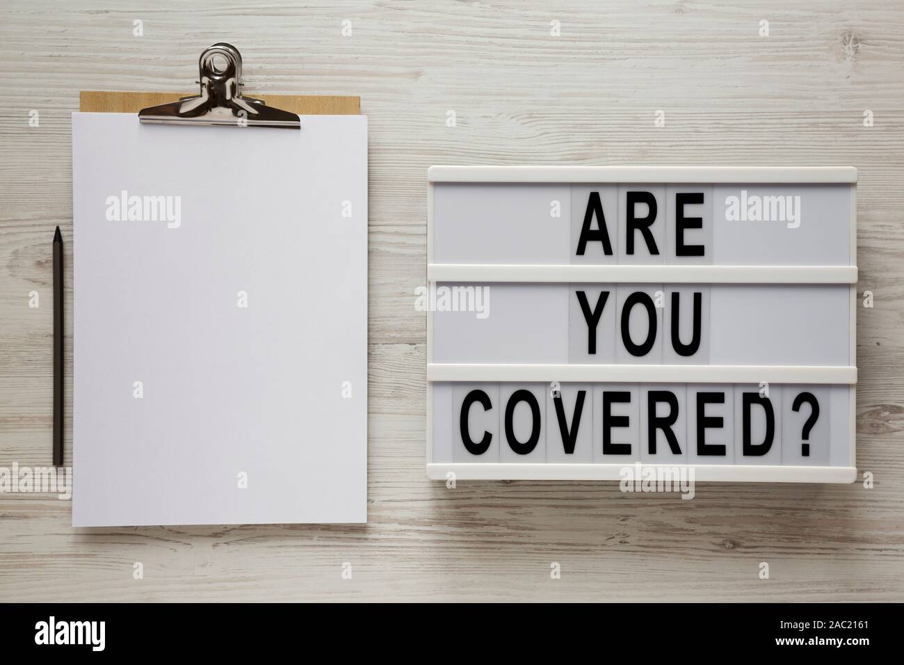 'Are you covered?' words on a lightbox, clipboard with blank sheet of ...