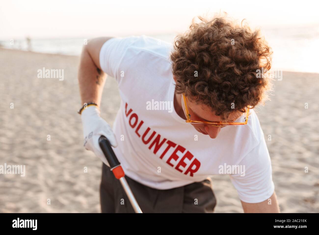 Image of male caucasian volunteer wearing uniform t-shirt cleaning ...