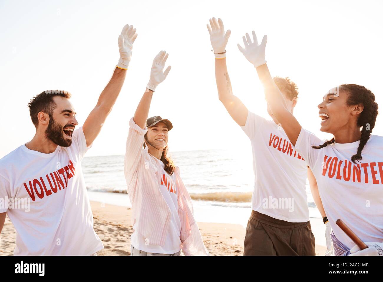Group of young cheerful friends volunteers cleaning beach from rubbish ...