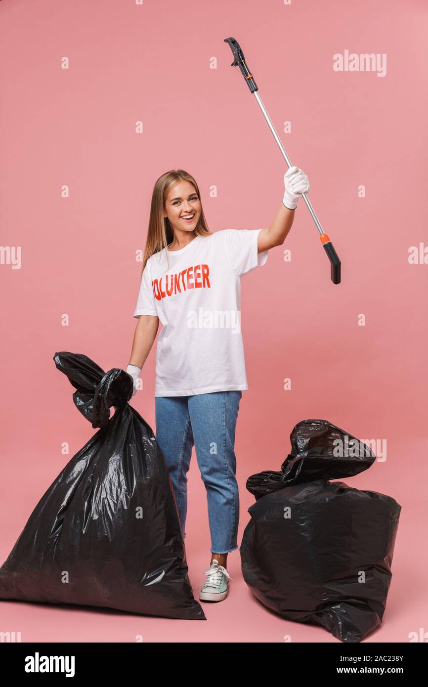 Image of happy woman volunteer in uniform t-shirt picking up litter in ...
