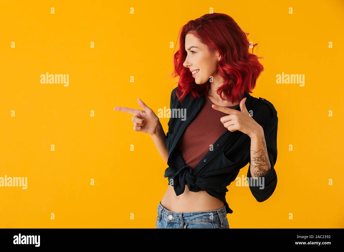 Image of nice cheerful woman with curly red hair smiling and pointing ...