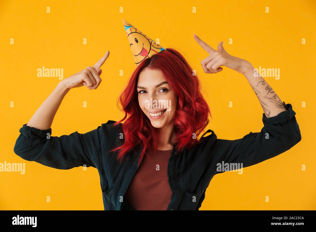 Image of cute delighted woman wearing party corn smiling and pointing ...