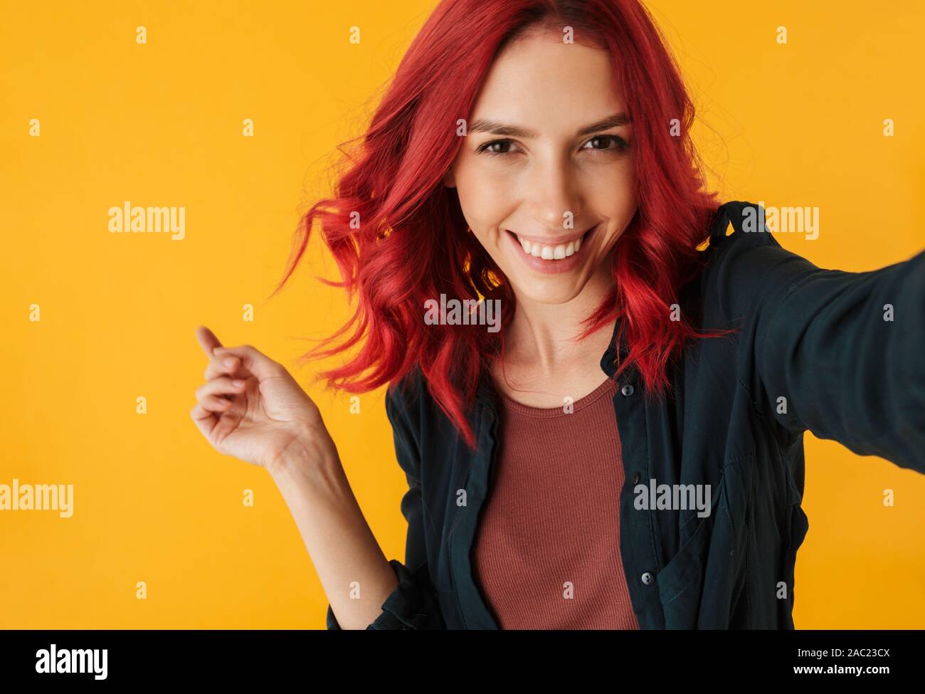 Image of smiling cute woman with curly red hair looking at camera and ...
