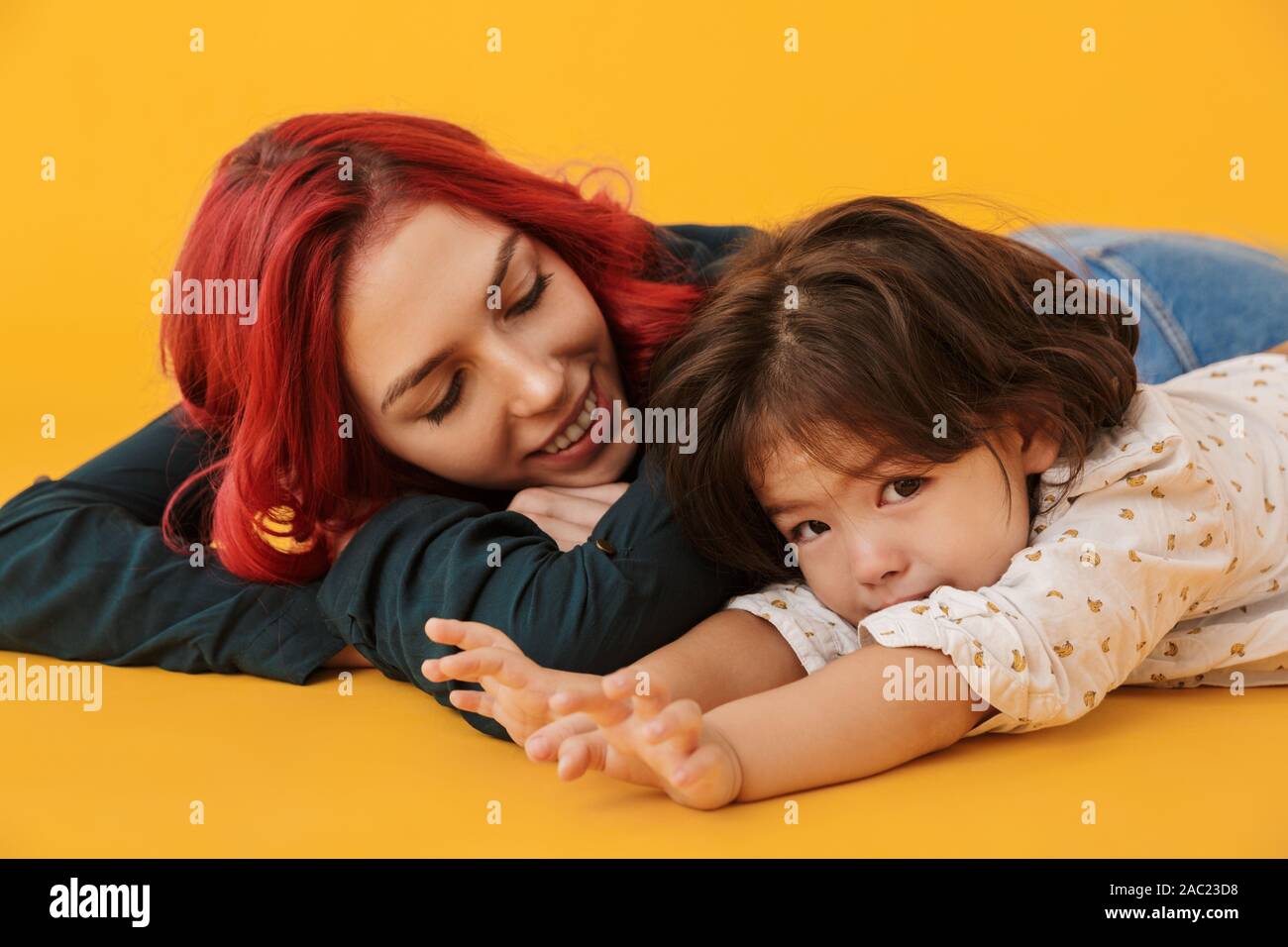Image of cheerful pretty woman and her daughter smiling and lying on ...