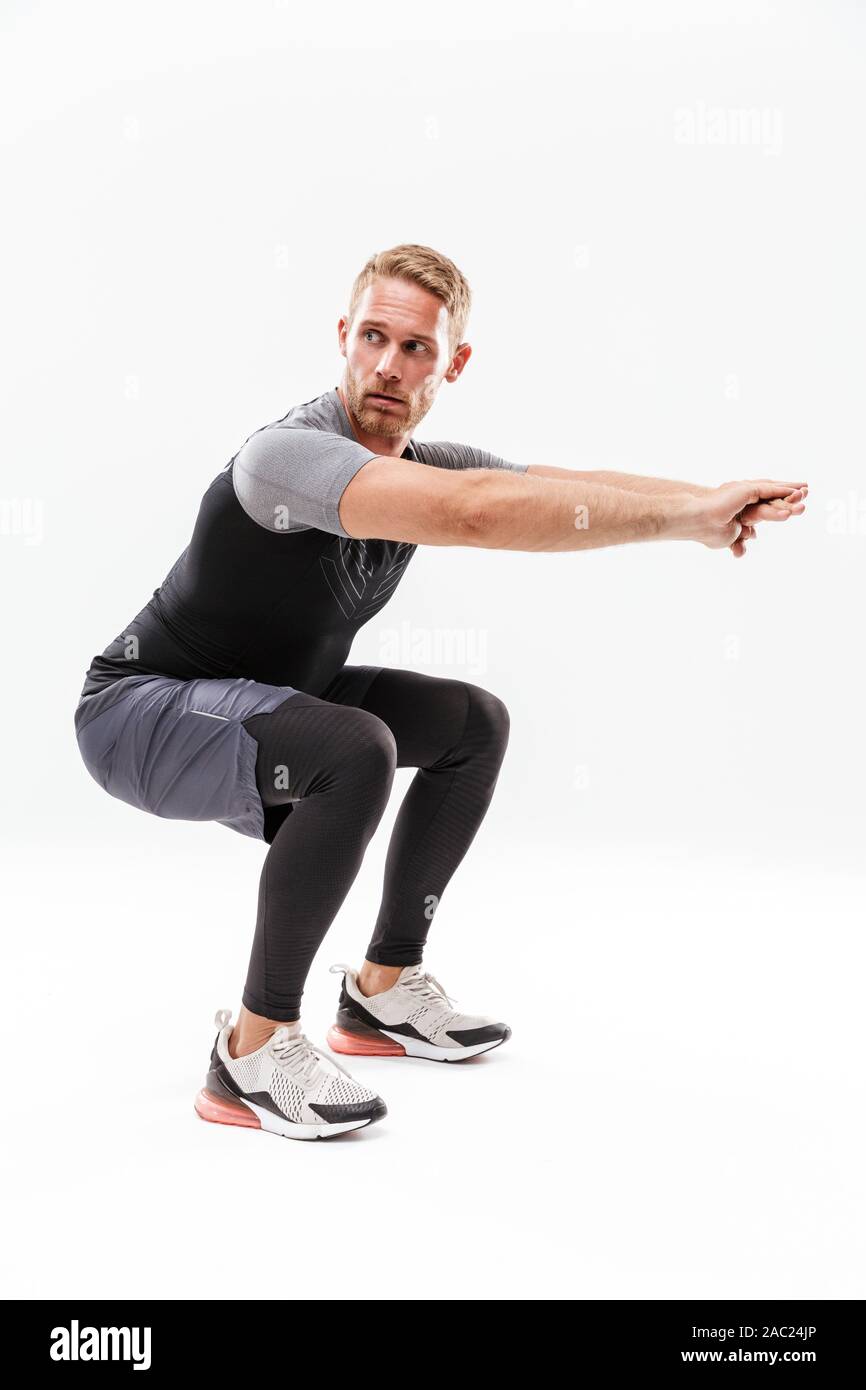 Full length of a handsome young concentrated sportsman doing squats ...