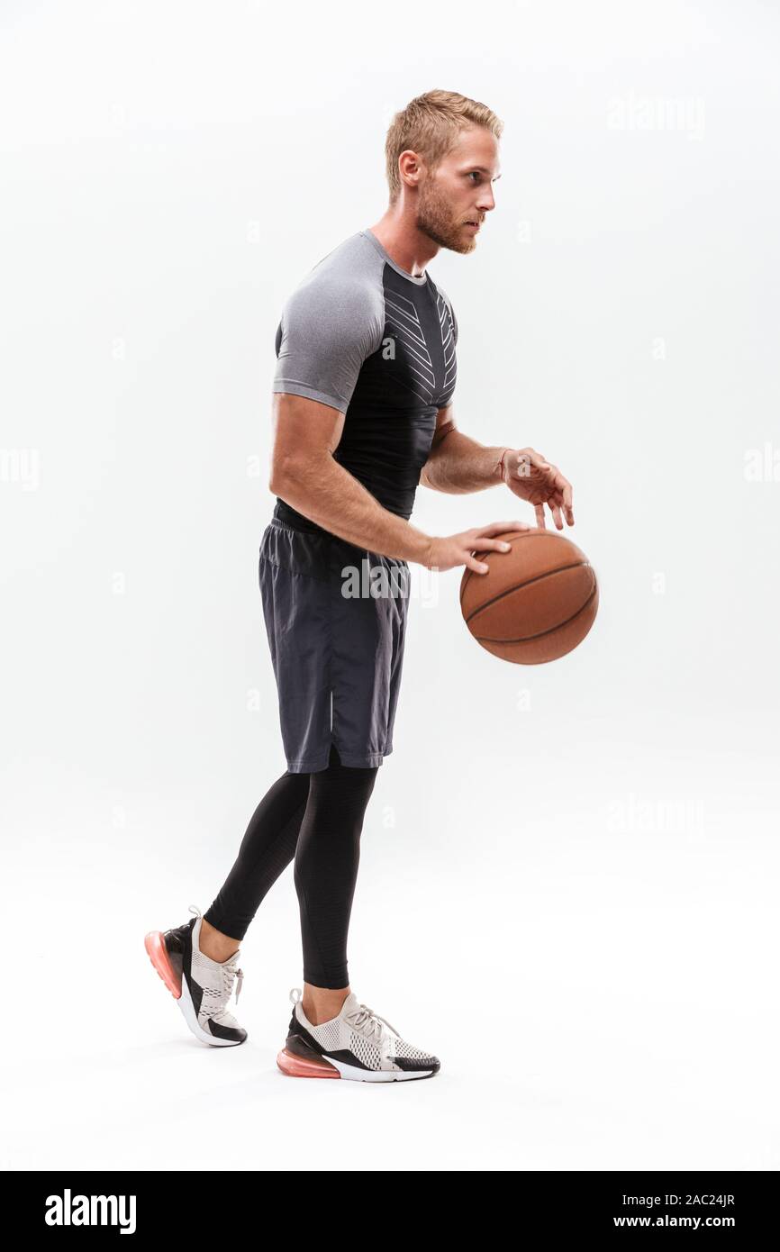 Full length of a focused young fit sportsman playing basketball ...