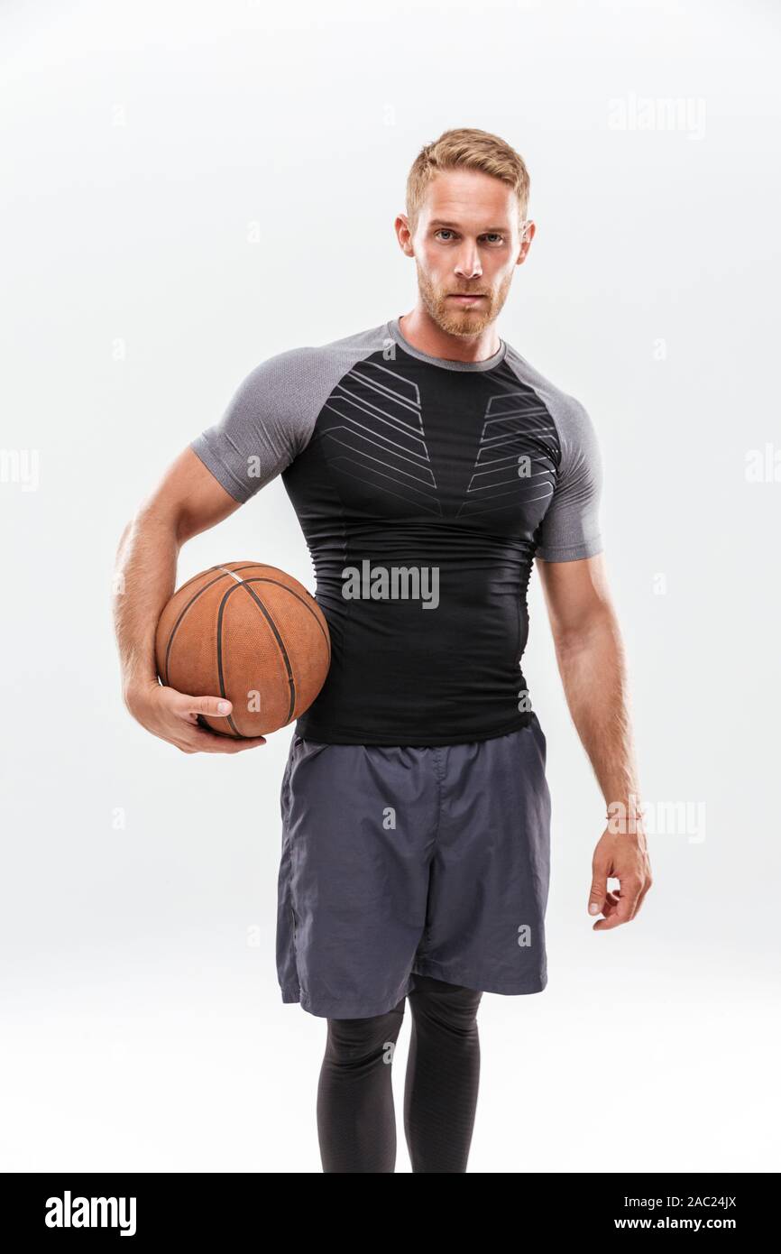 Focused young fit sportsman playing basketball isolated over white ...