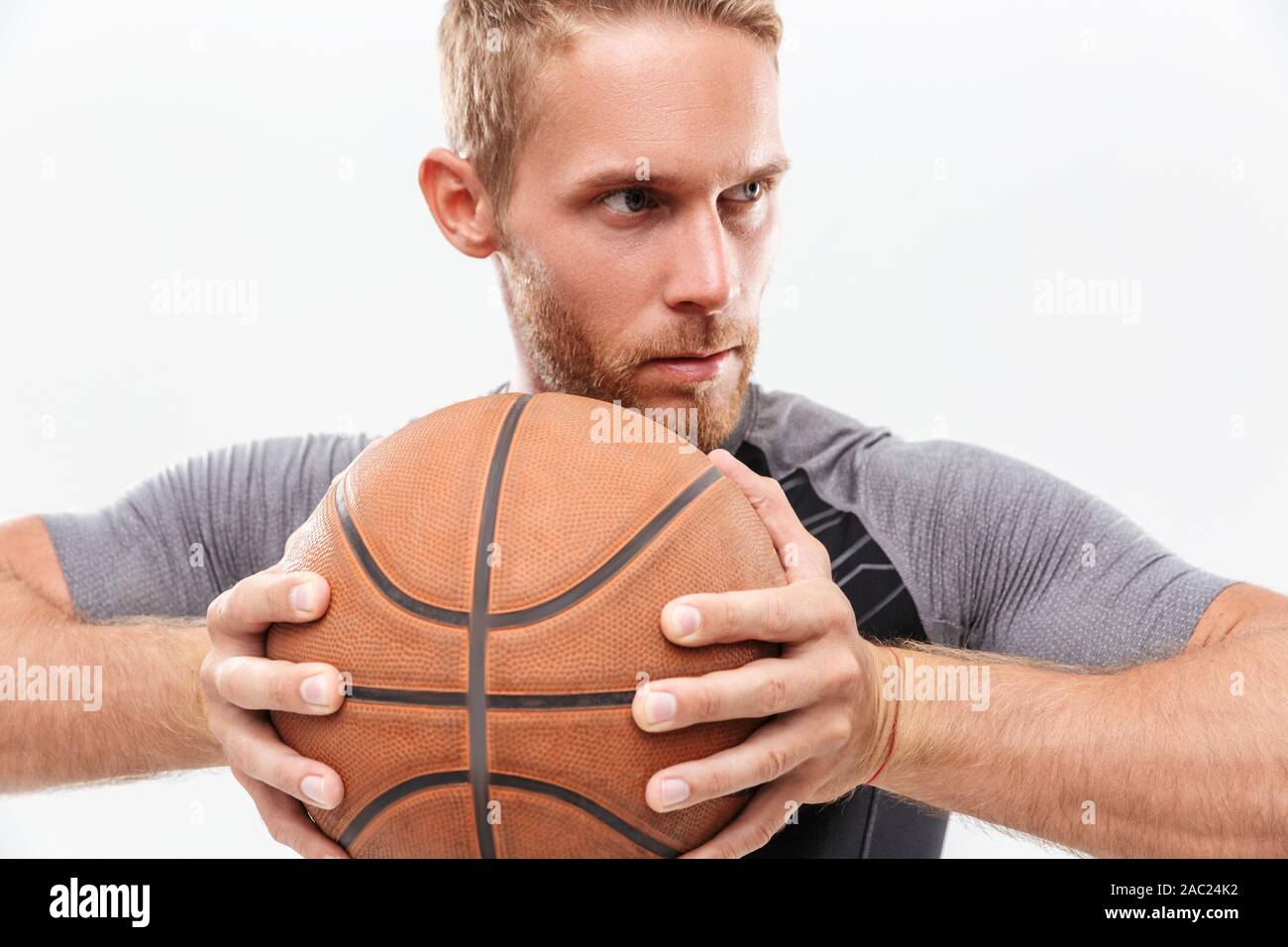 Focused young fit sportsman playing basketball isolated over white ...