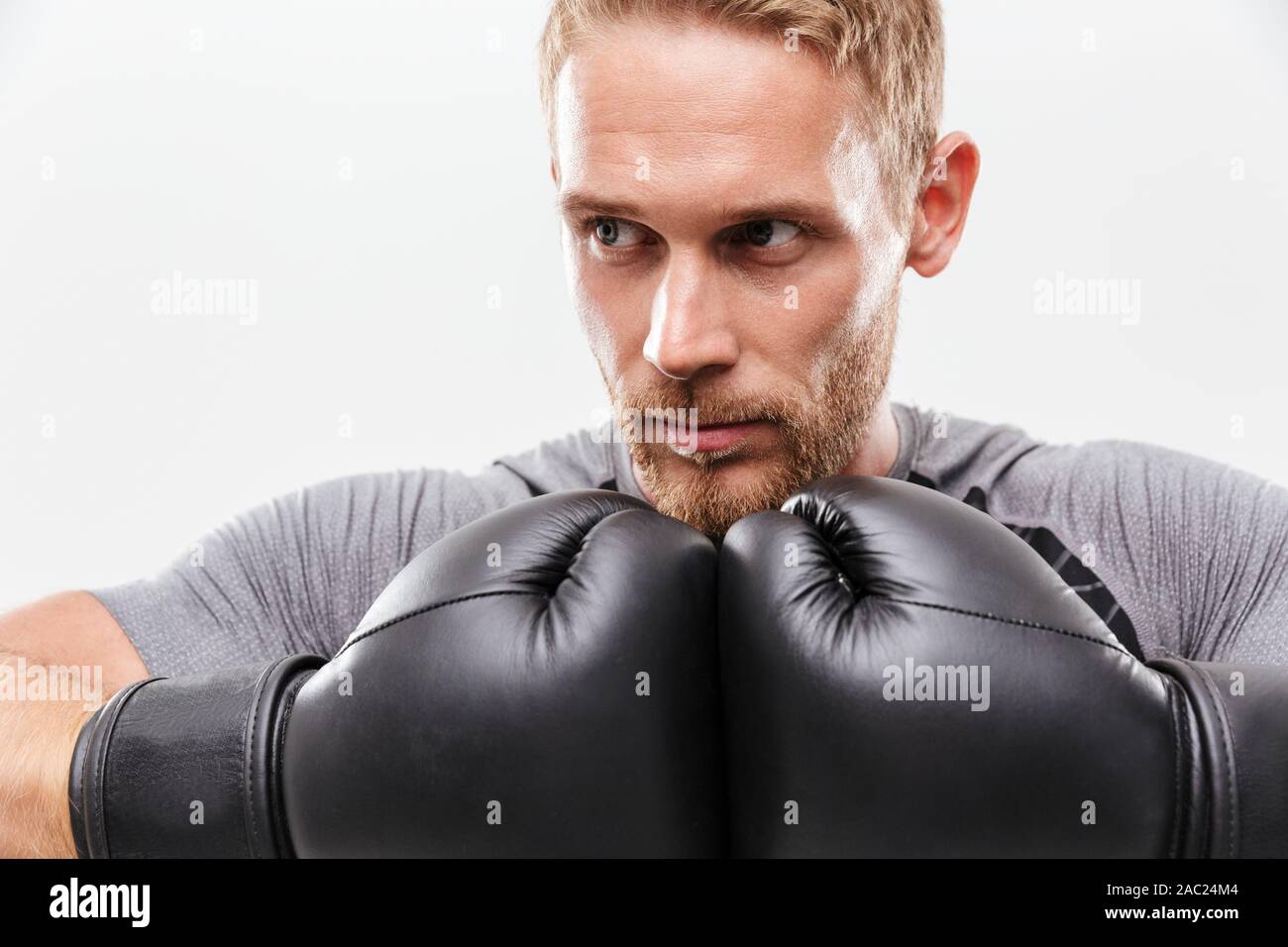 Confident young fit sportsman wearing boxing gloves isolated over white ...