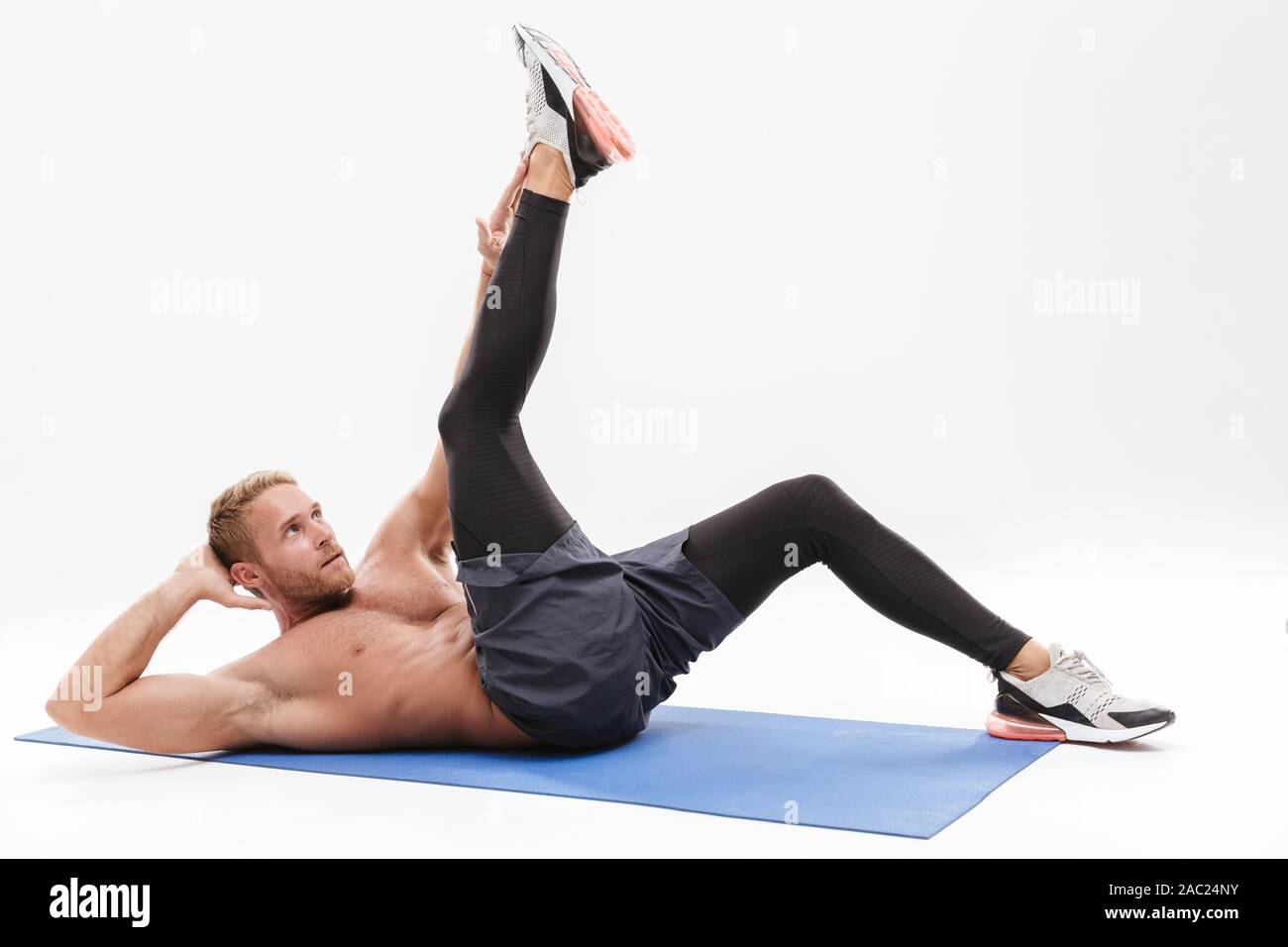 Confident attractive sportsman doing crunches on a fitness mat isolated ...