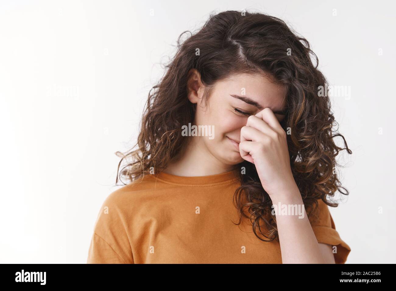 Upset crying young caucasian curly-haired girl hiding tears sobbing ...