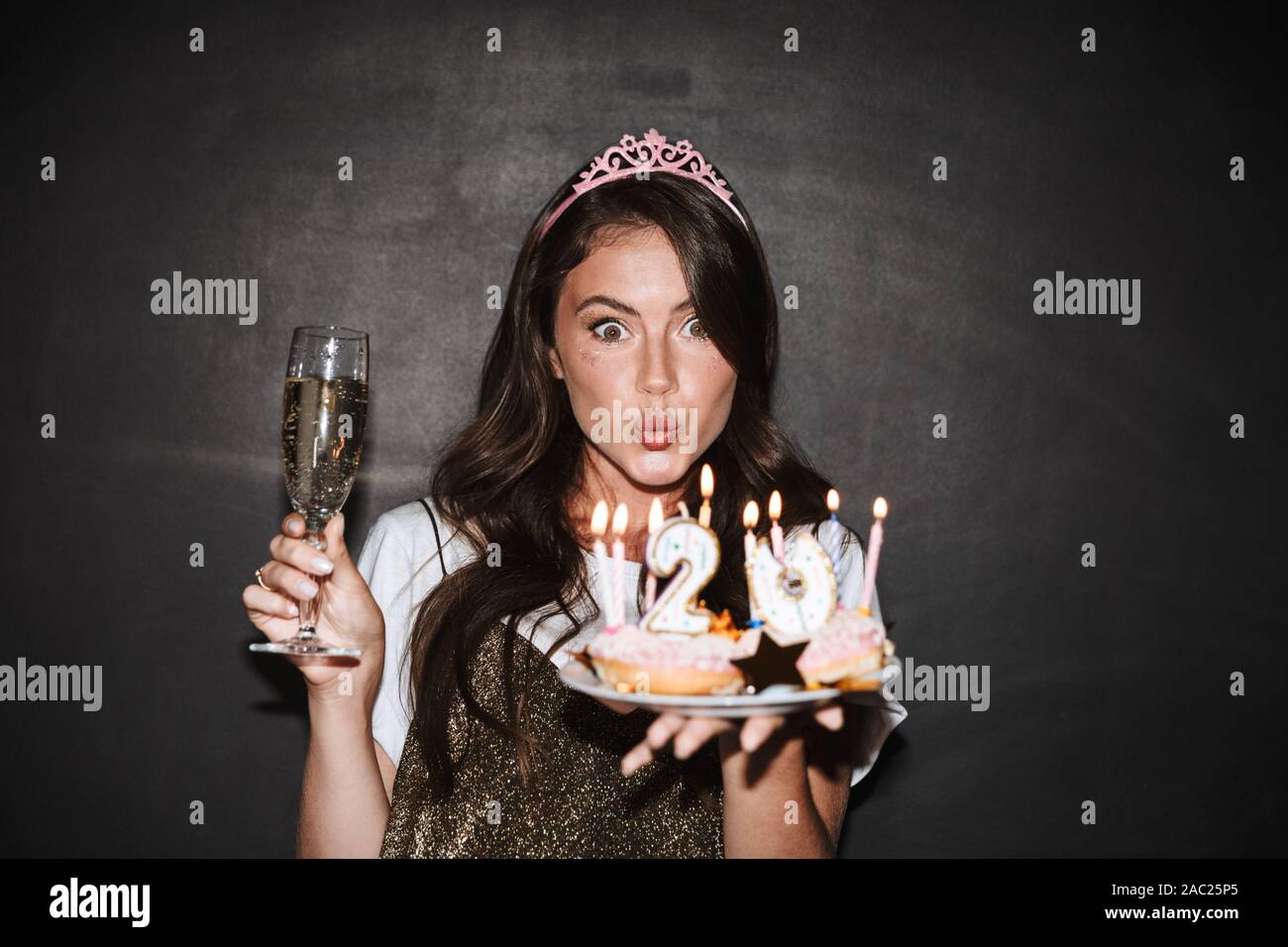 Image of nice funny woman in tiara holding cakes and glass of champagne ...