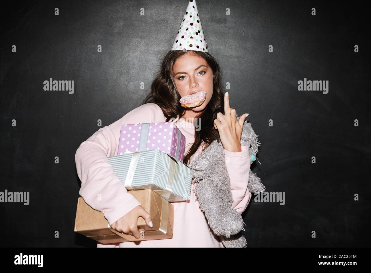 Image of sassy woman in party cone holding gift boxes and showing ...
