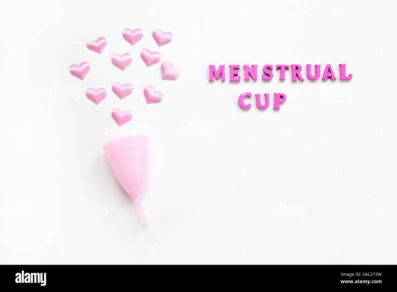 Pink menstrual cup on white background with small hearts and ...