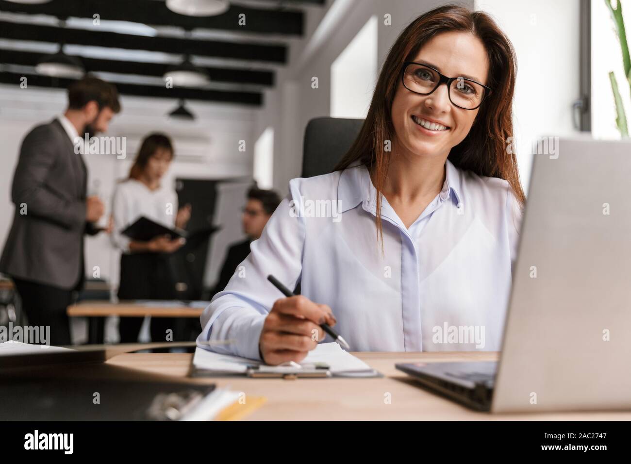Photo of smiling businesswoman wearing eyeglasses working with ...