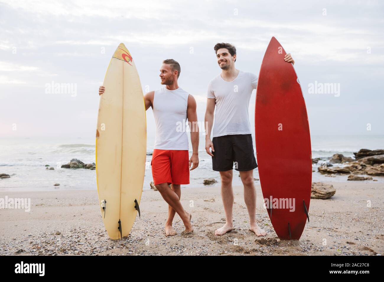 Image of a happy young cheery positive two men surfers friends with ...