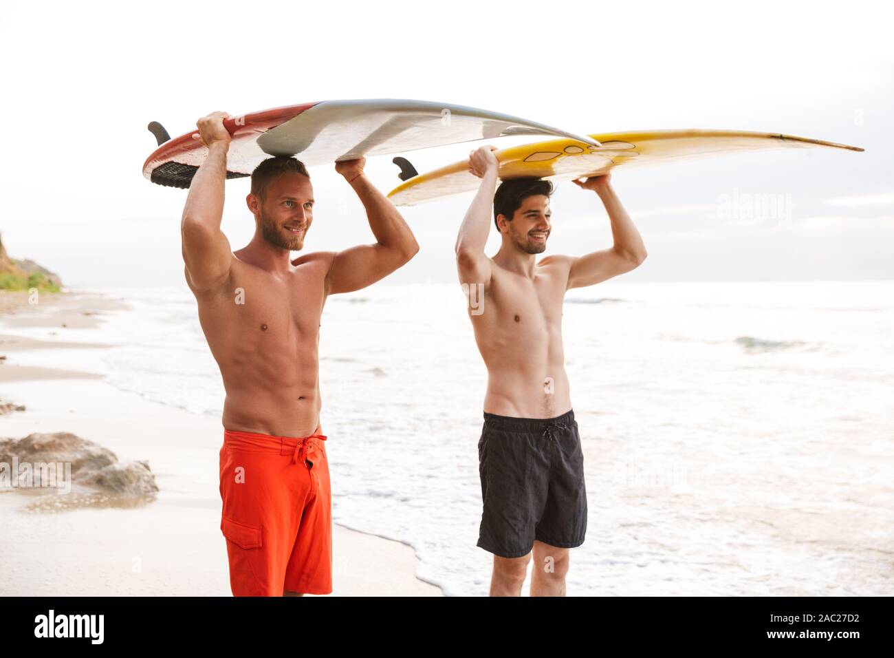 Image of optimistic smiling young two men surfers friends with surfings ...