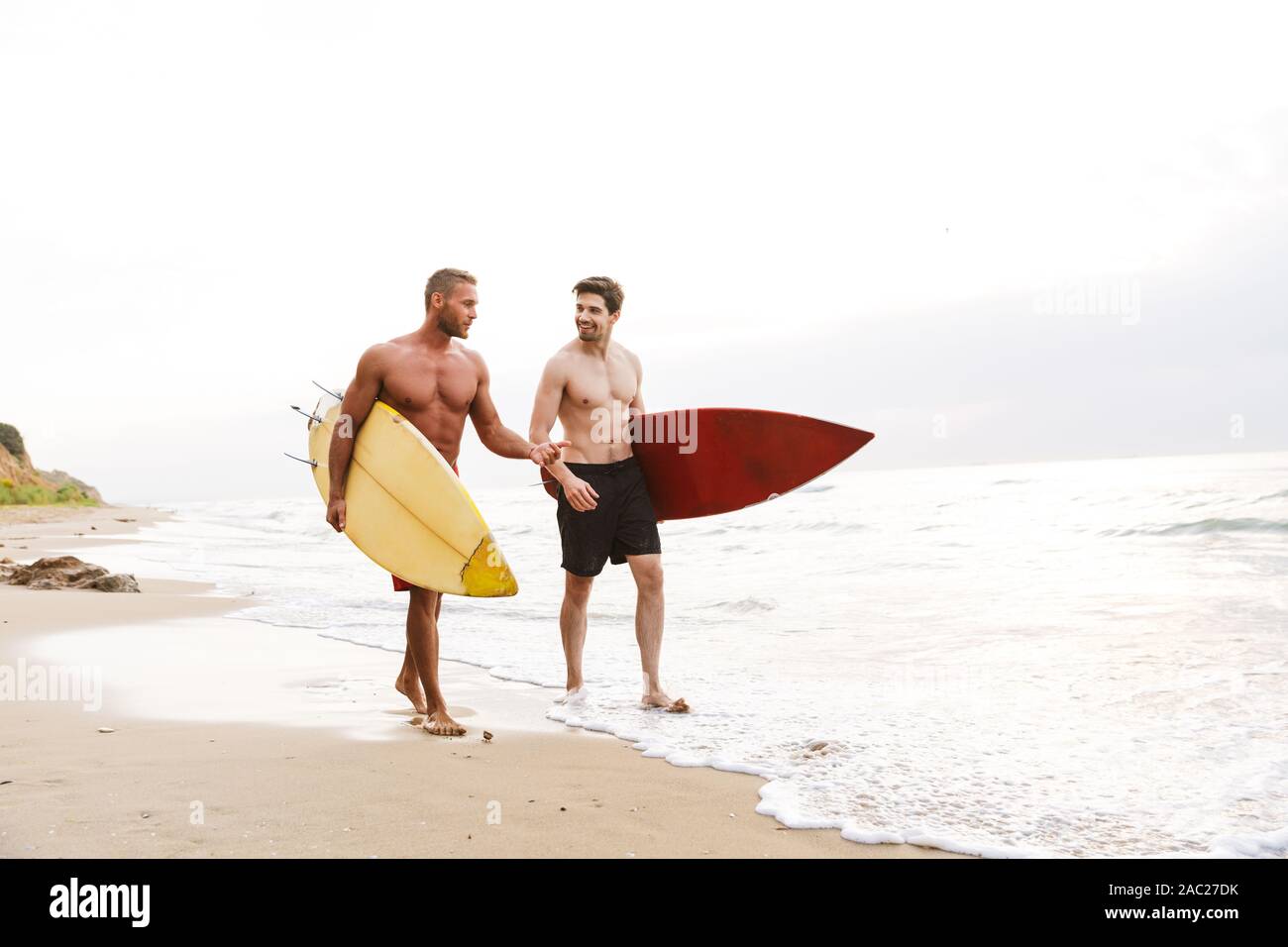 Image of a cheerful young optimistic two men surfers friends with ...
