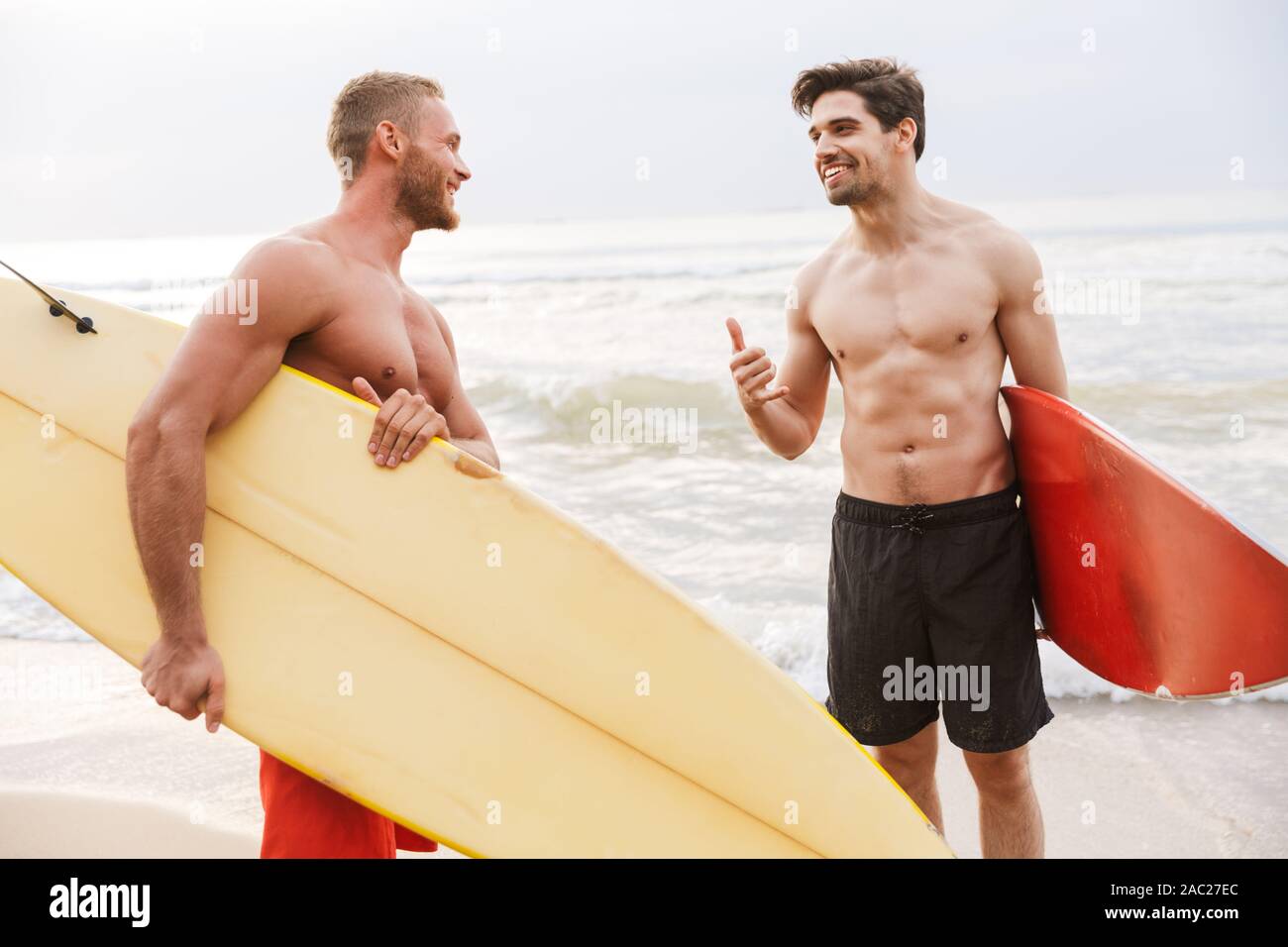 Image of a happy young cheery positive two men surfers friends with ...