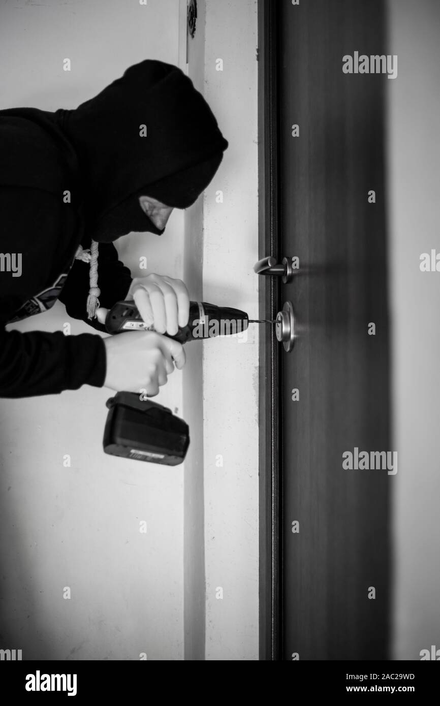Crime, robbery, masked thief, burglar, trying to break into a flat, a ...
