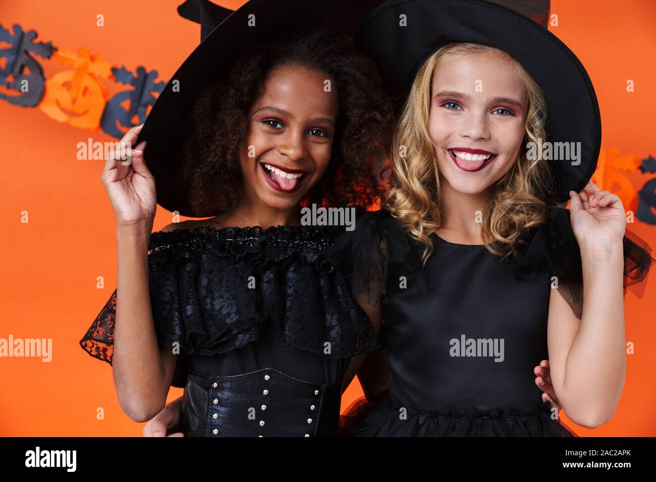 Image of amusing witch girls in black halloween costumes smiling and ...