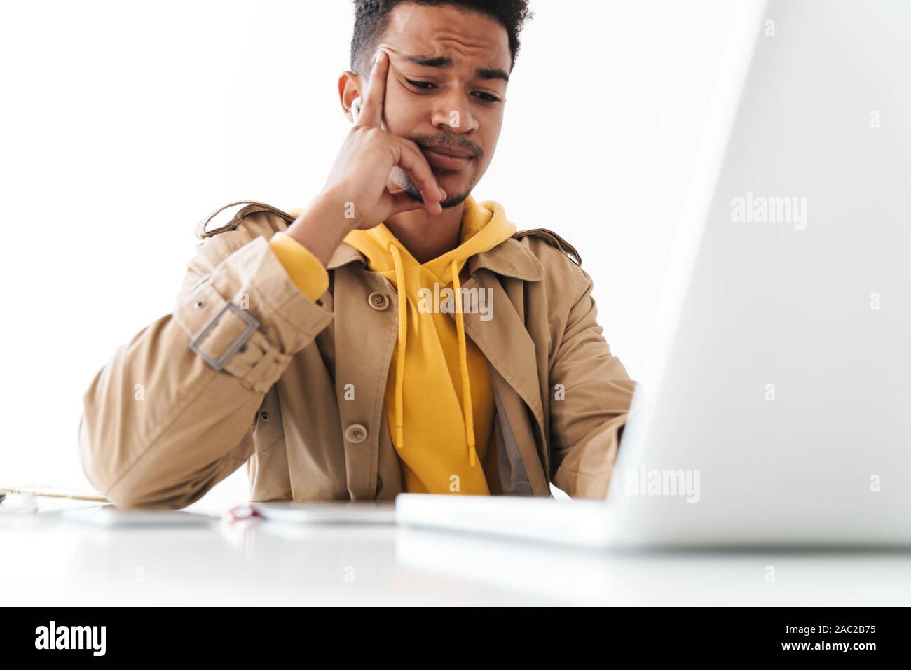 Image of young african american man thinking while working on laptop ...