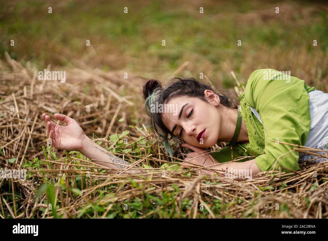 Girl lying in a wheat field and posing on hay dry grass, summer season ...