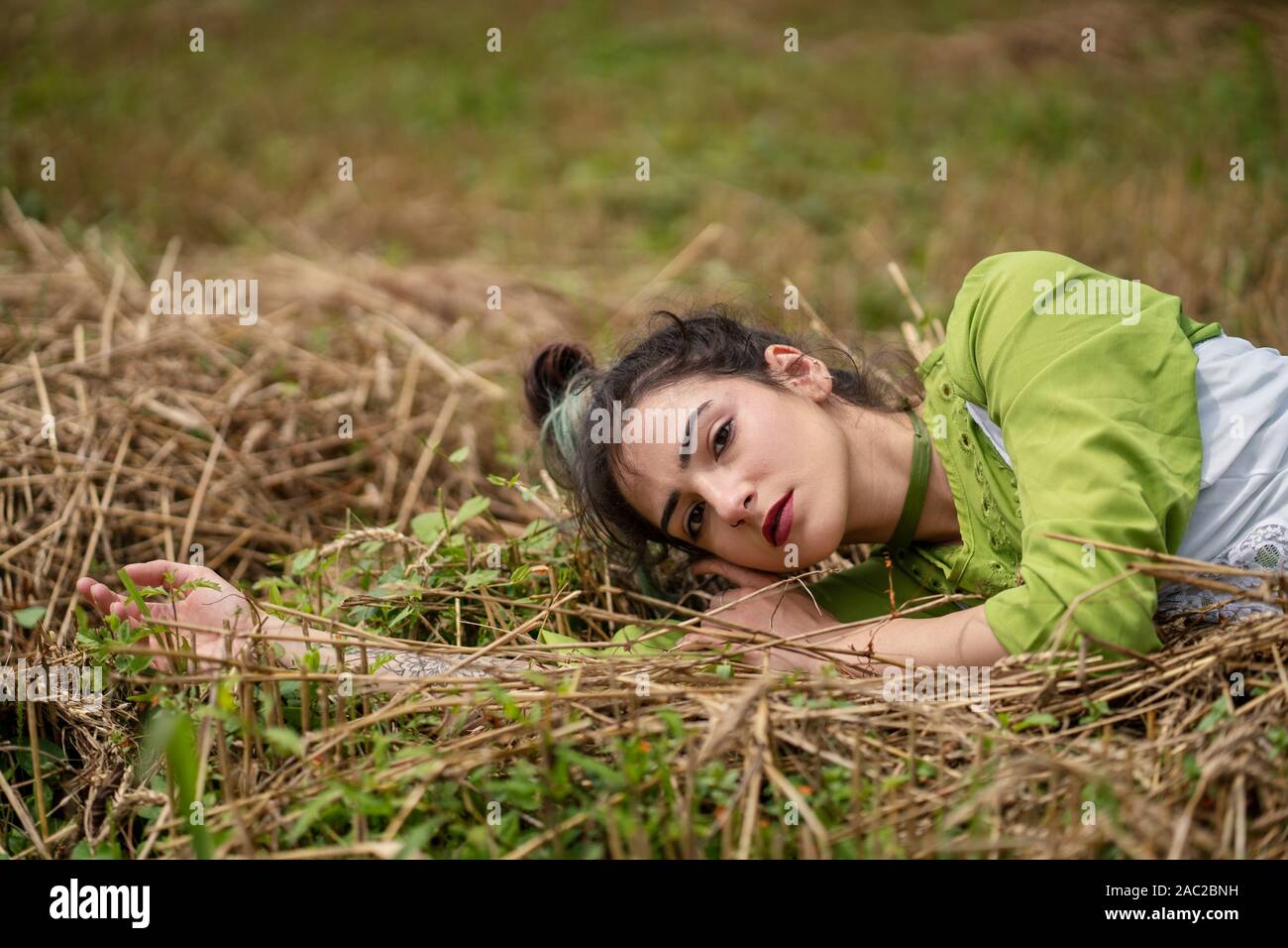 Girl lying in a wheat field and posing on hay dry grass, summer season ...